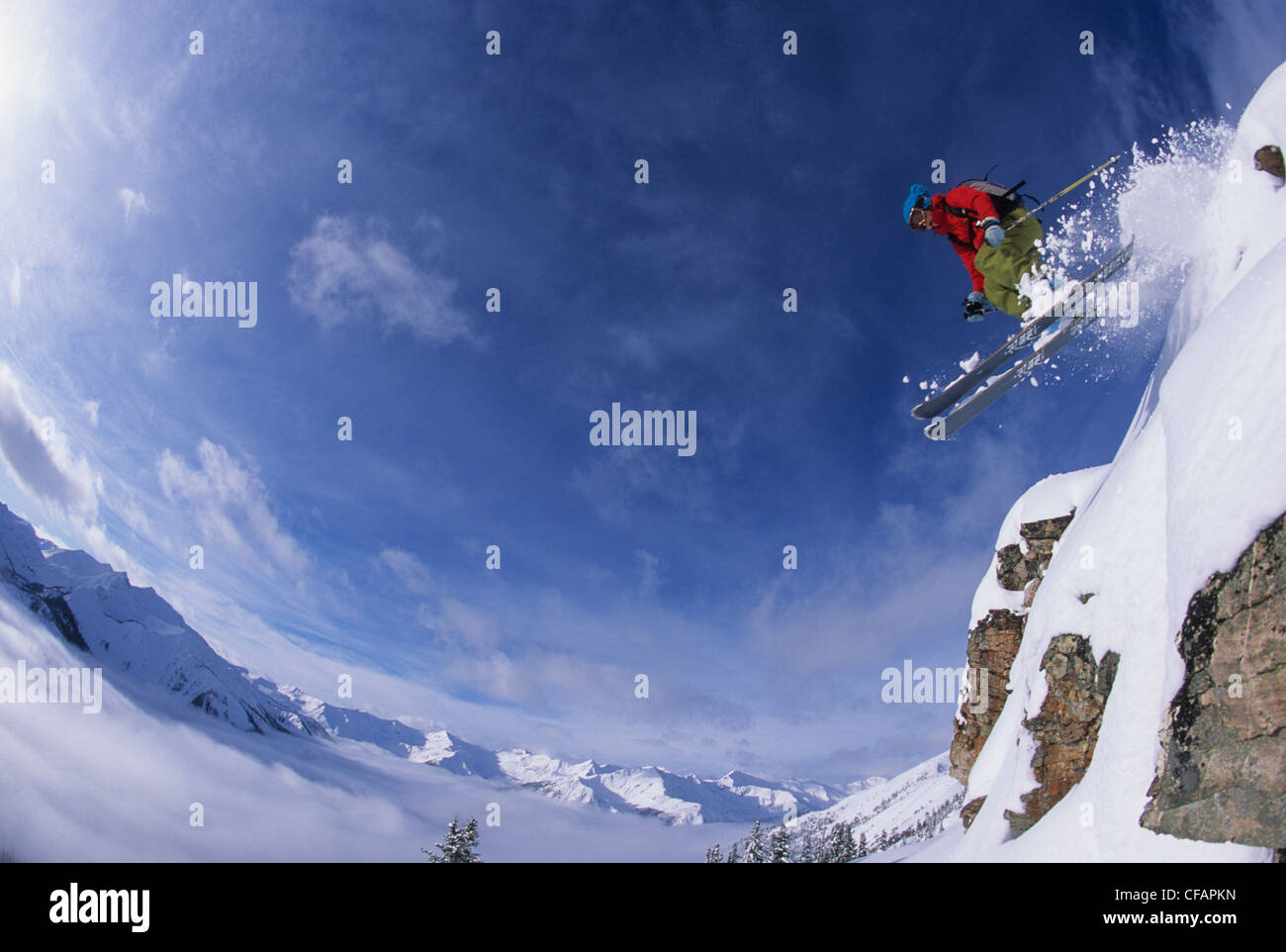 A female skier jumping a cliff in the backcountry of Kickinghorse ...