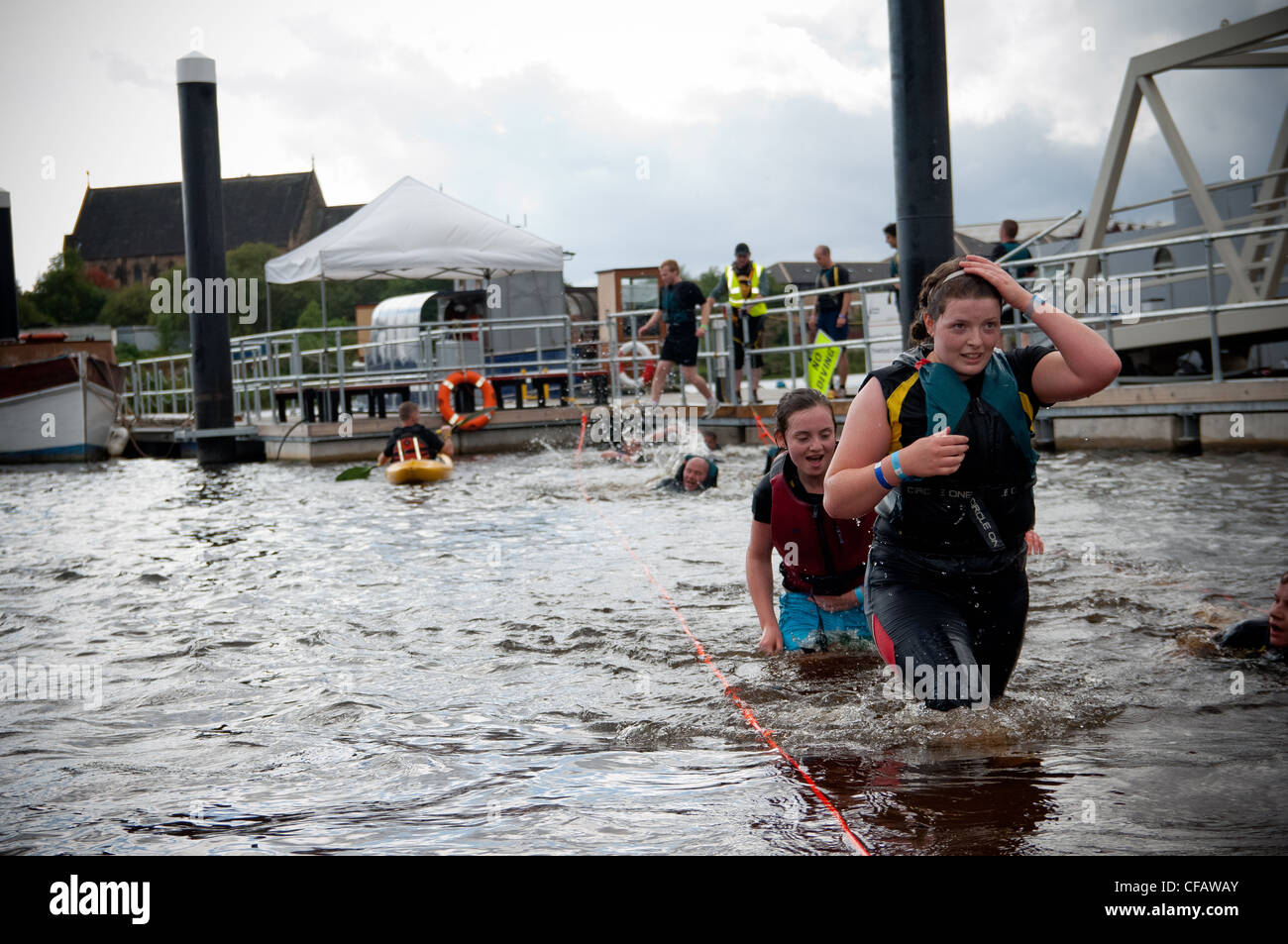 Competitors wade through water obstacle during event Stock Photo - Alamy