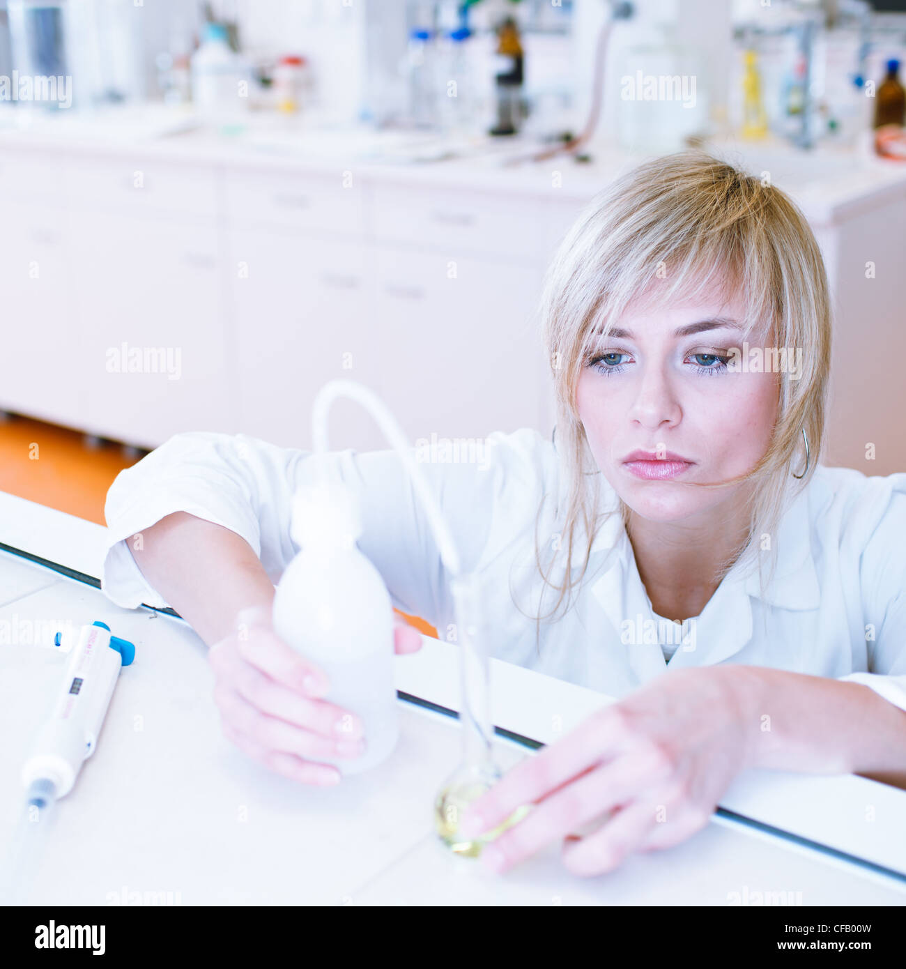 female researcher carrying out research experiments in a chemistry lab ...