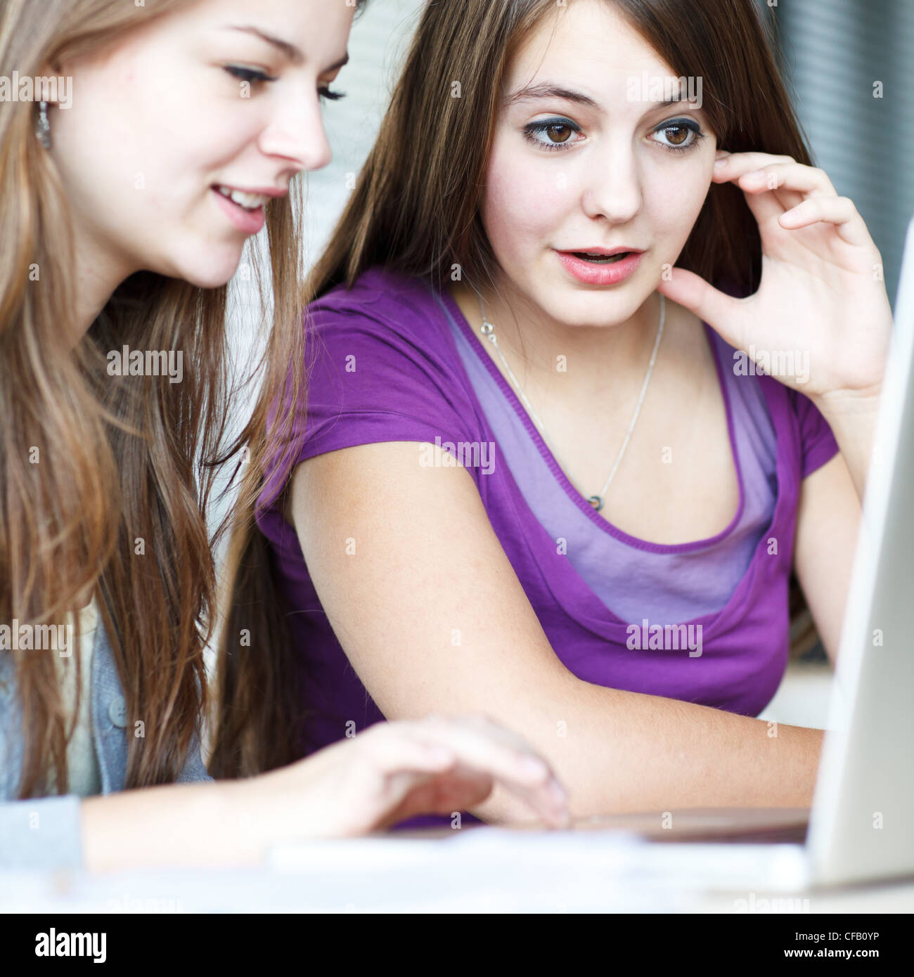 Two female college students working on a laptop computer during class ...