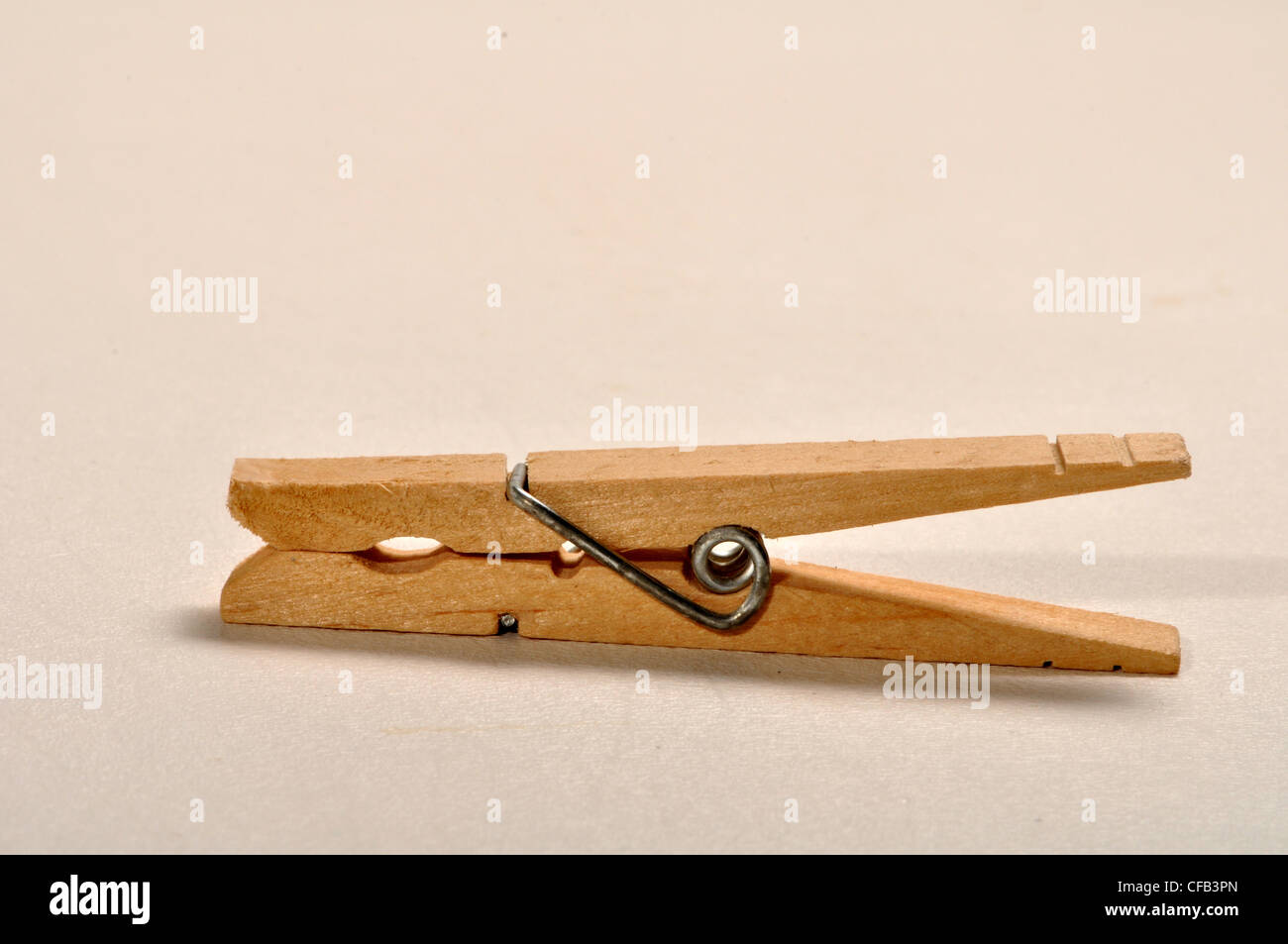 A single wooden clothes pin is laying on a white background Stock Photo ...