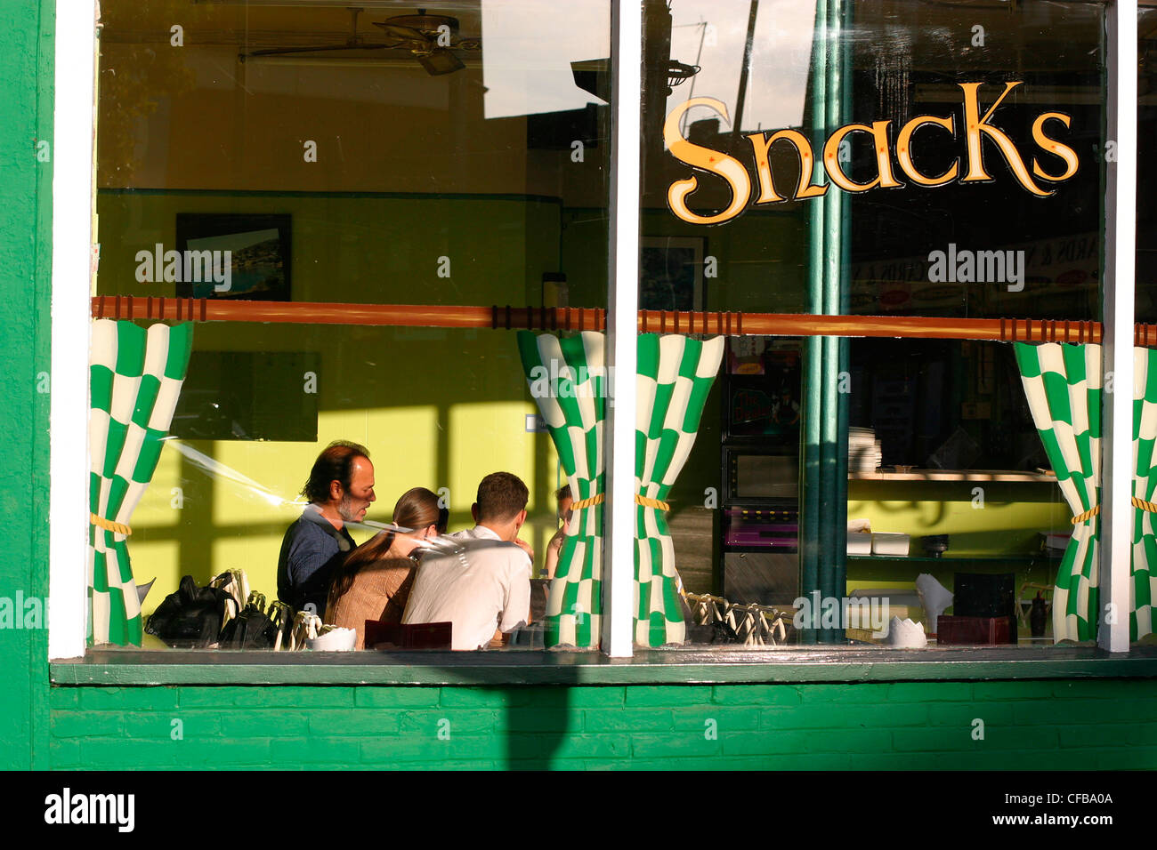 People eating inside a cafe, with the sun falling on them through the ...