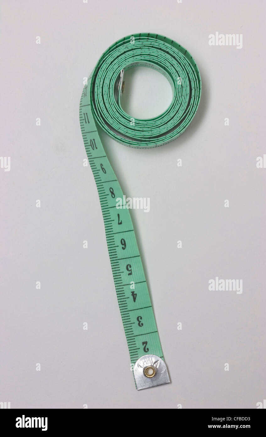 Green tape measure coiled up on plain background Stock Photo - Alamy