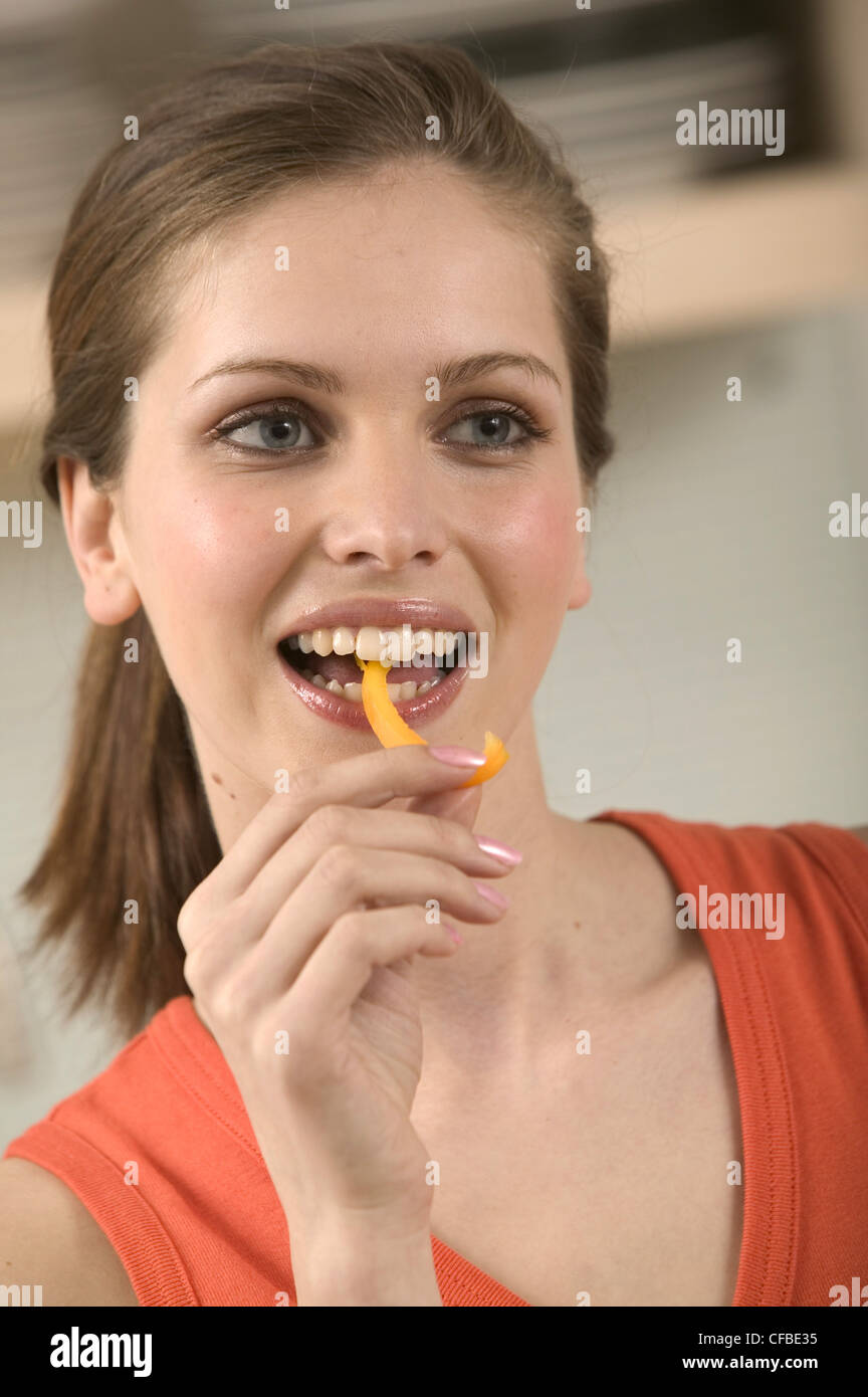 Female brunette hair off face wearing orange v neck top eating slice of ...