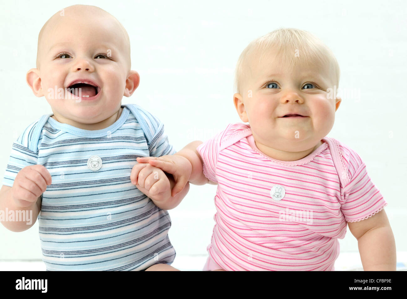 Two babies looking to distance laughing and smiling, male baby on left ...