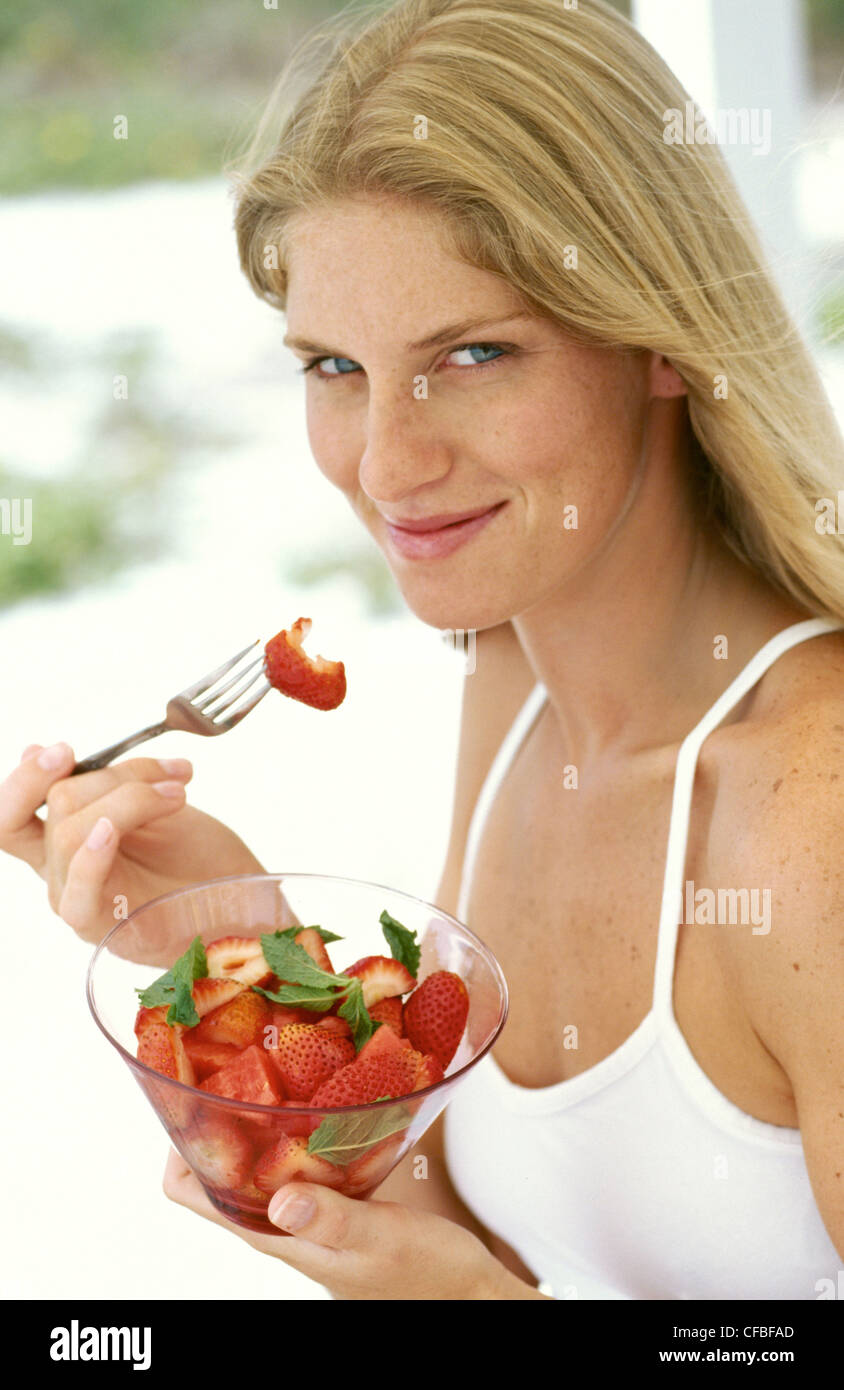 Female Long Blonde Hair Wearing White Vest Top Eating Strawberry And