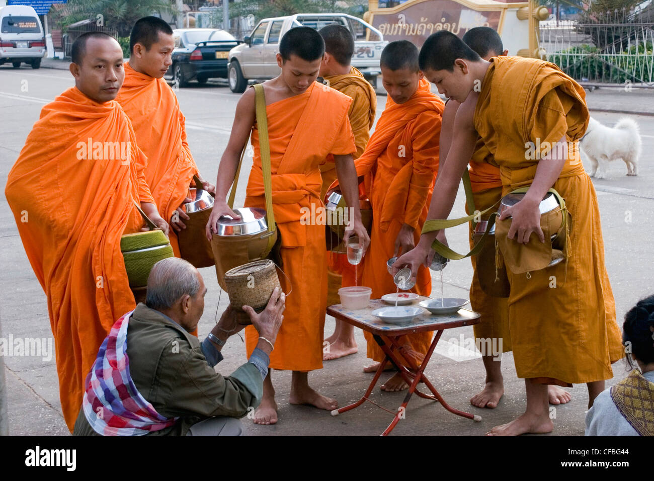 A man is making an offering of rice to Buddhist monk's during morning ...