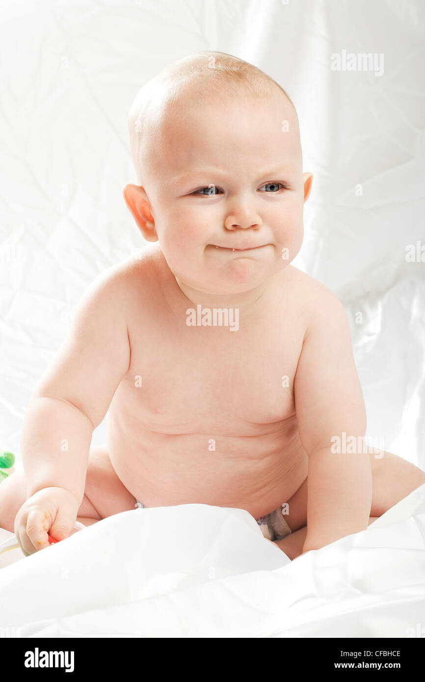 A baby sitting wearing a nappy grimacing Infobeauty Stock Photo - Alamy