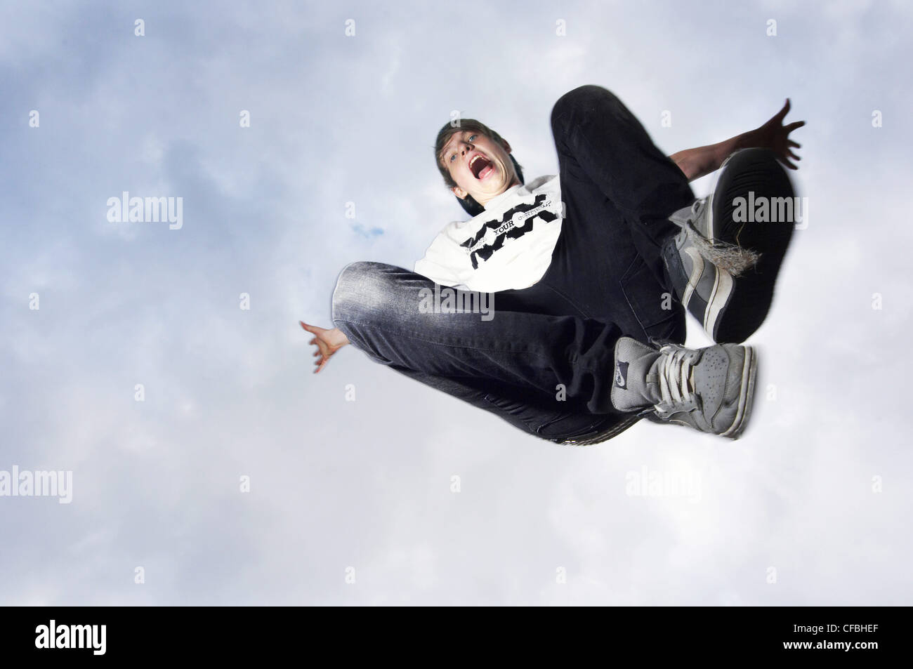 View from below of a teenage boy jumping high into the air the sky ...