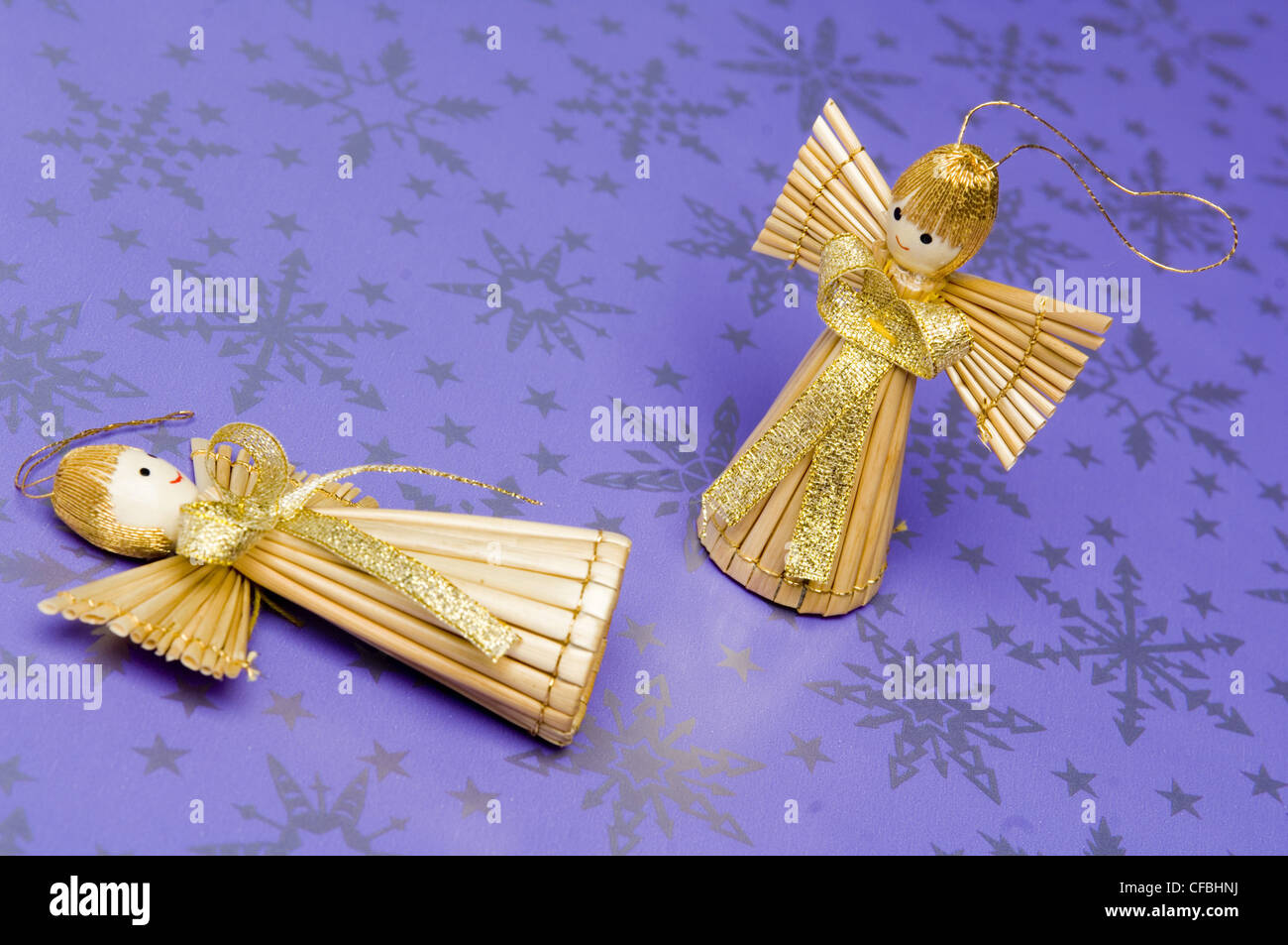 Two Christmas angels make from straws, one standing upright, one laid ...