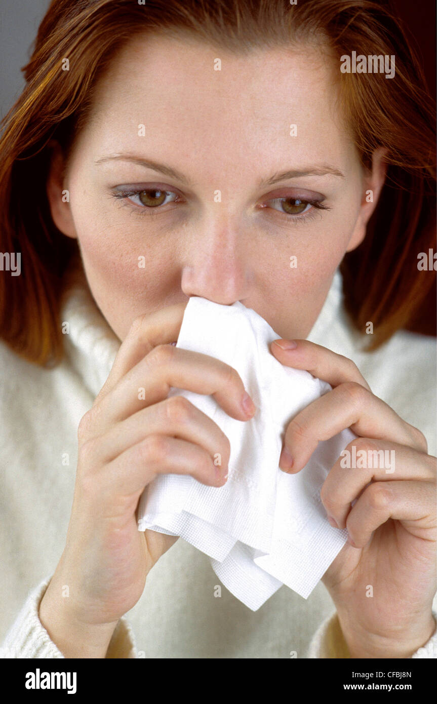 Cropped image of a brunette female wiping nose with a tissue, wearing a ...
