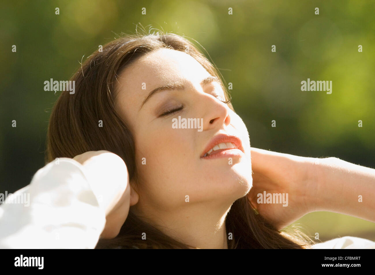 Female wearing cream jacket hands behind neck, head tipped back, eyes ...
