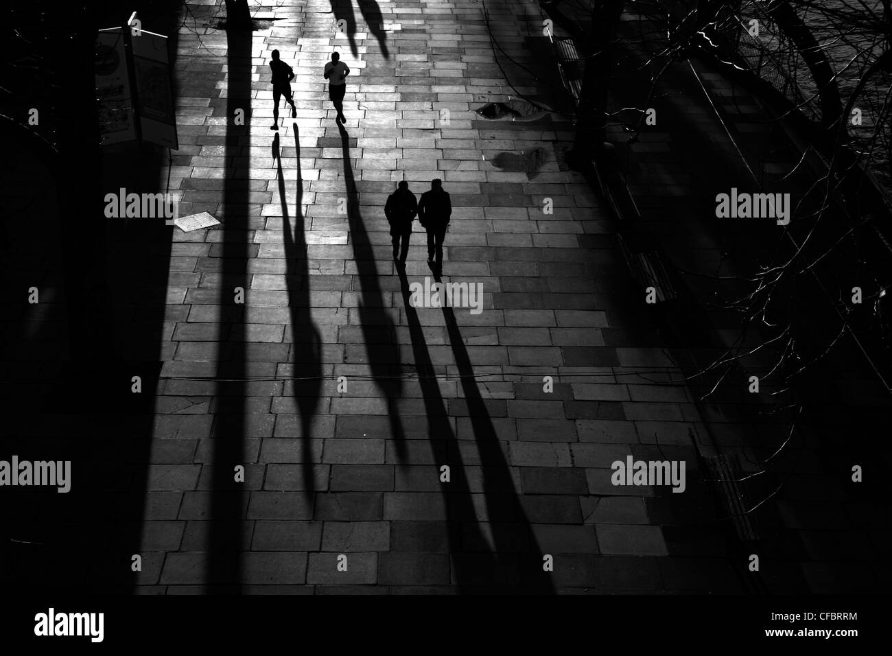 Shadows and silhouettes of pedestrians walking along the Queen's Walk ...