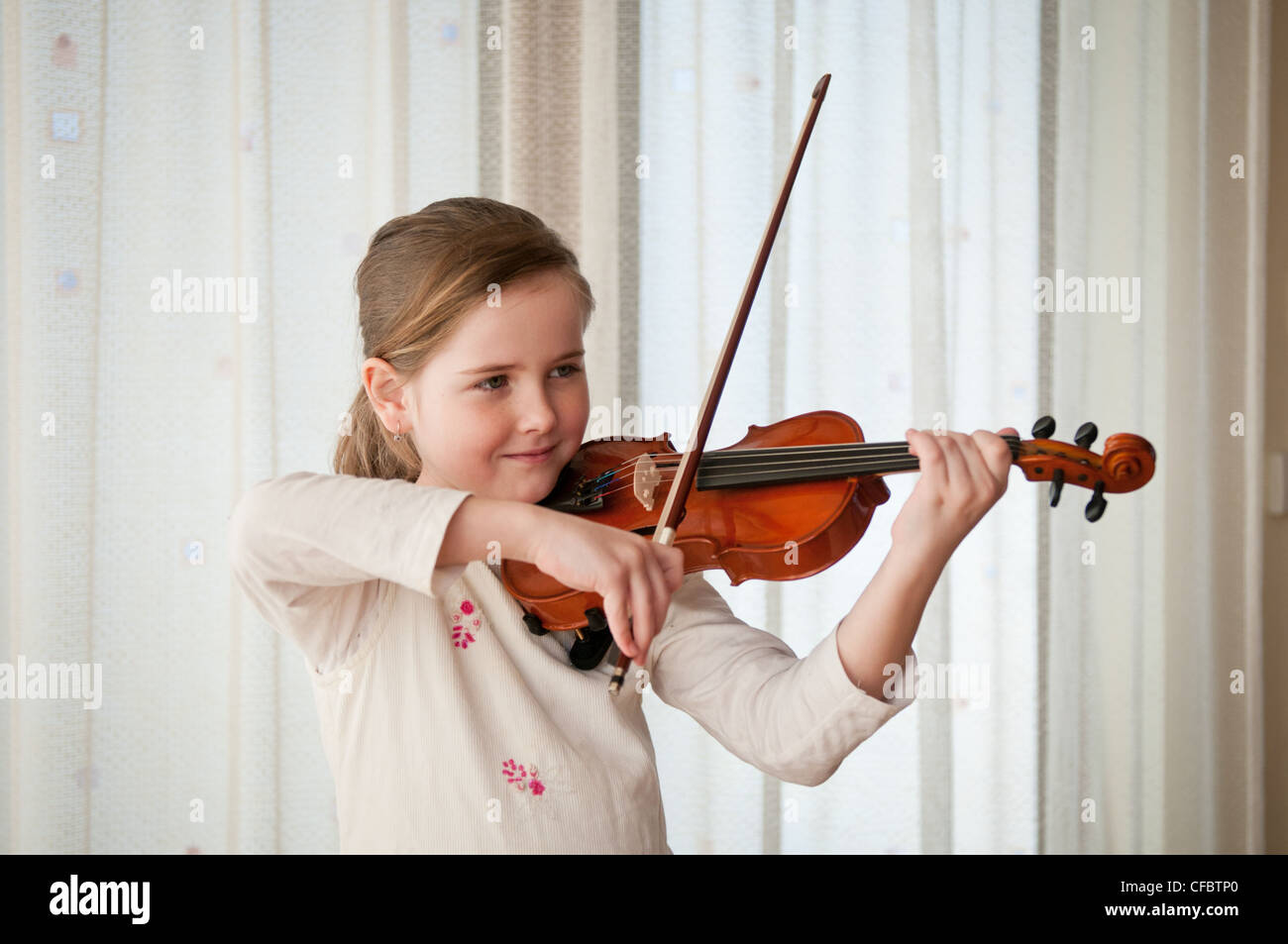 Cute child (little girl) playing violin and exercising at home Stock ...