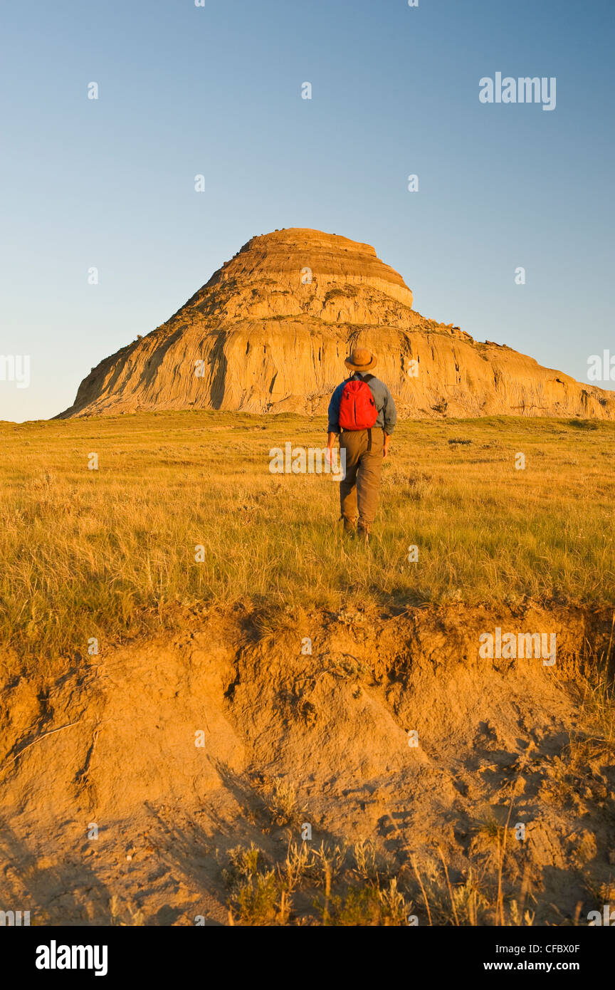 A hiker walks towards Castle Butte, Big Muddy Badlands, Saskatchewan ...