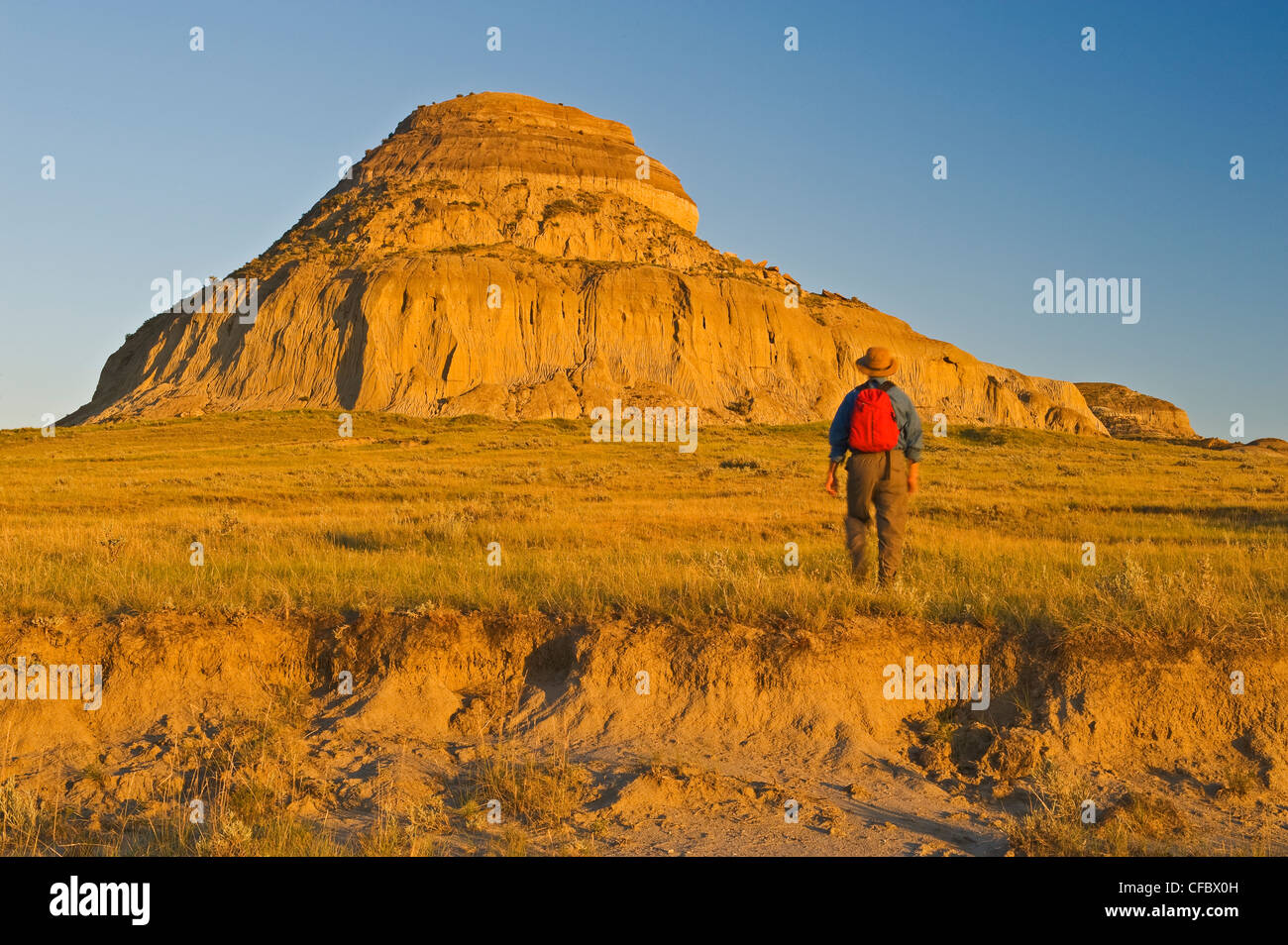 A hiker walks towards Castle Butte, Big Muddy Badlands, Saskatchewan ...