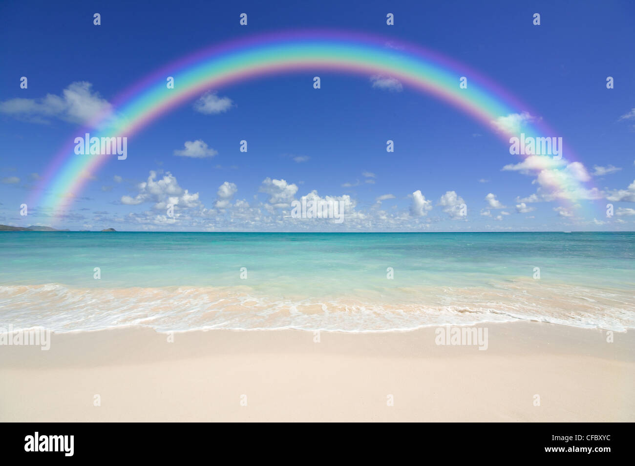 Colourful rainbow over a blue ocean with sandy beach in the foreground ...