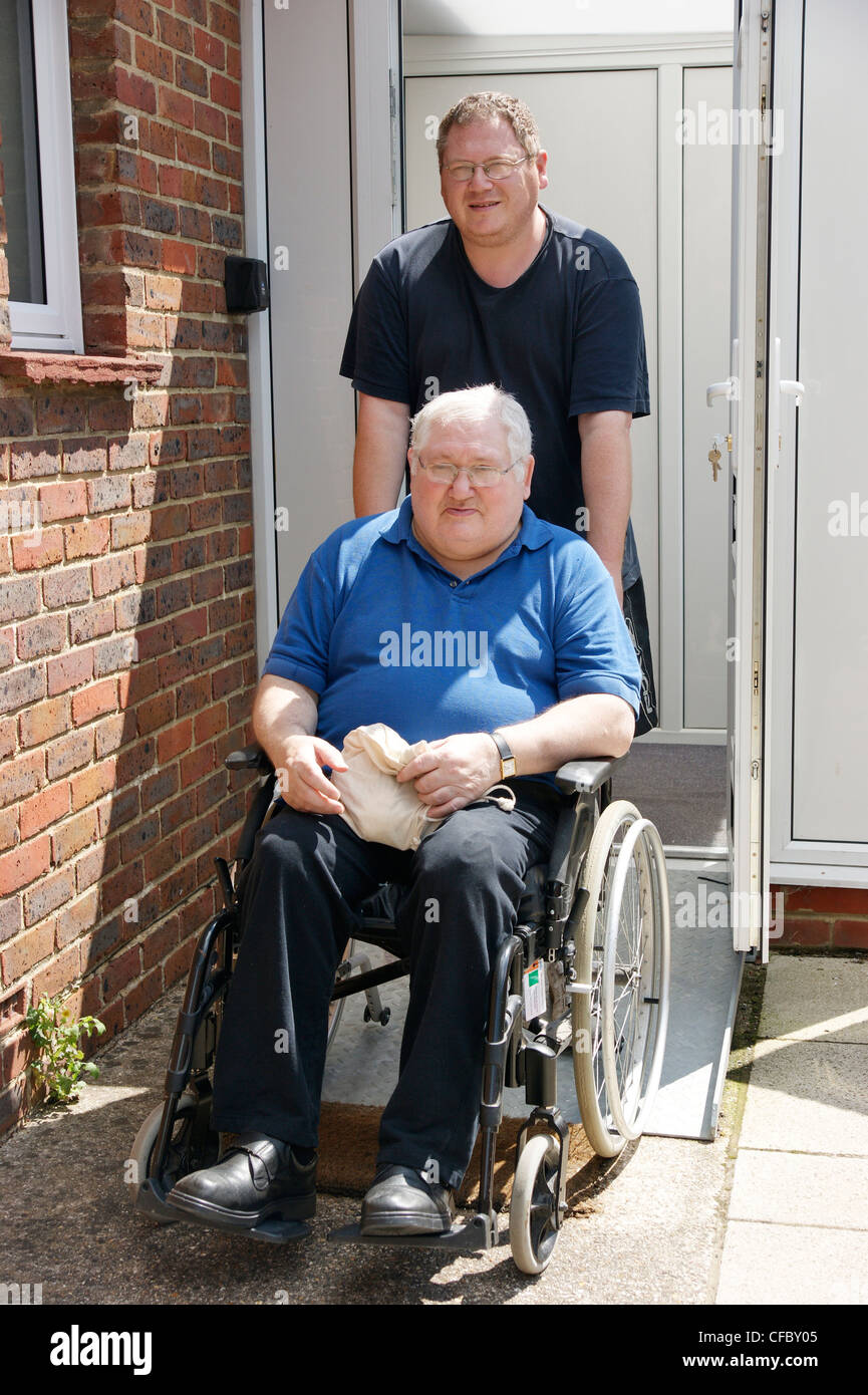 disabled elderly man in wheelchair with his carer son outside their ...