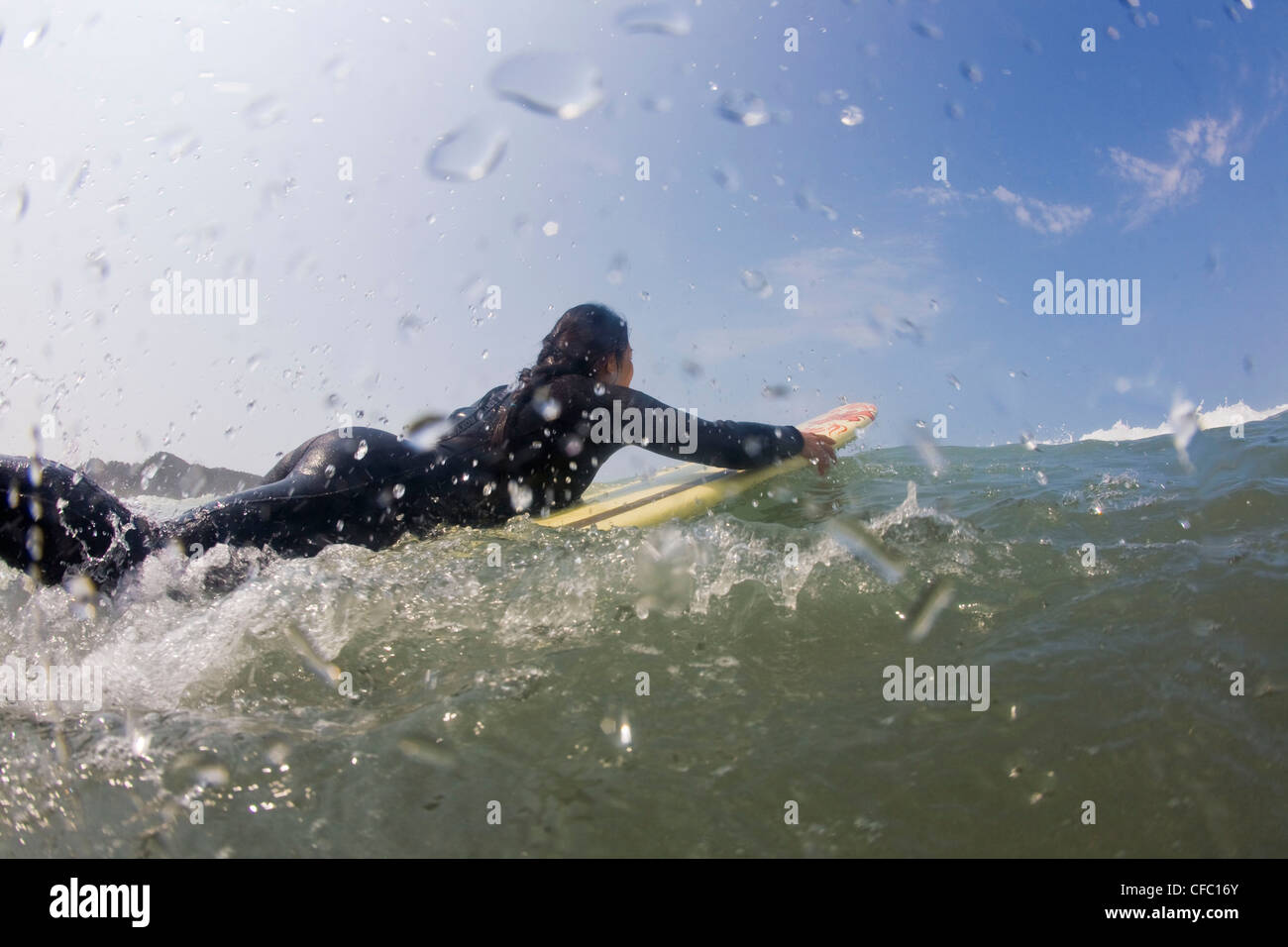 A female surfer paddling out at Cox Bay Stock Photo - Alamy