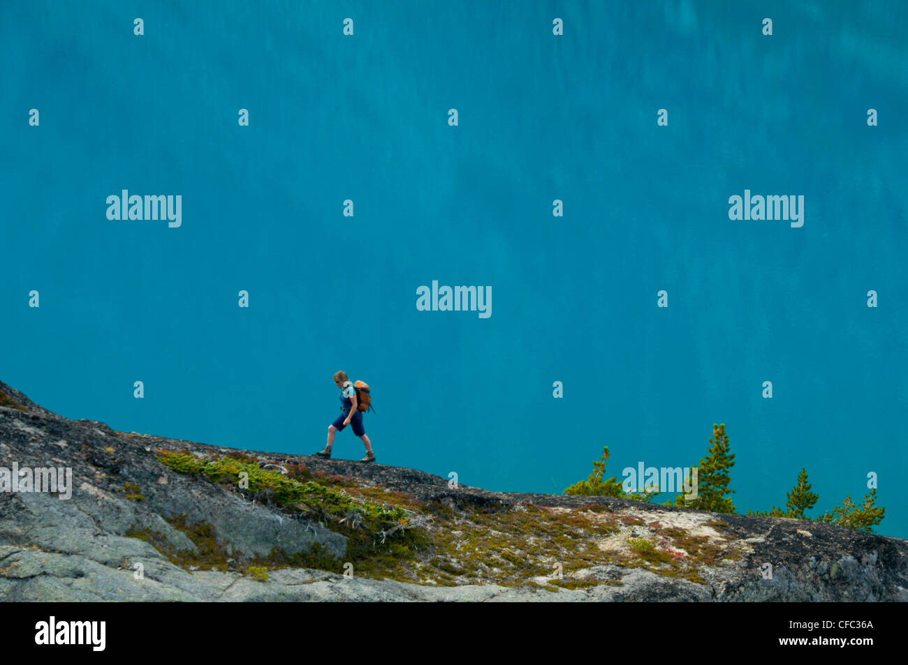A young woman hikes in front of a blue lake in the Niut Range, British ...
