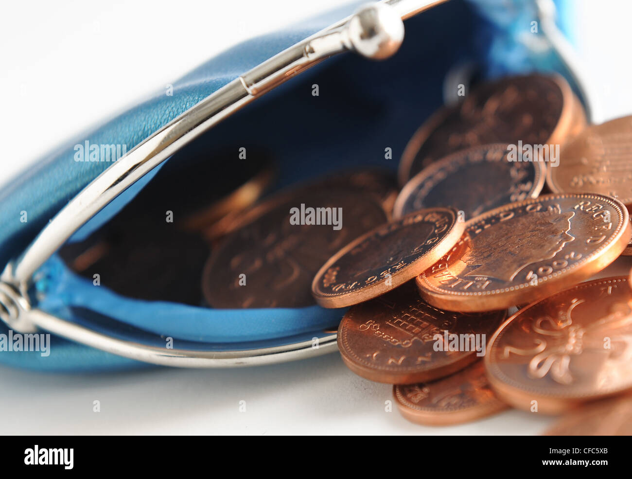 A still life image of pence coins falling out of a blue coin purse ...