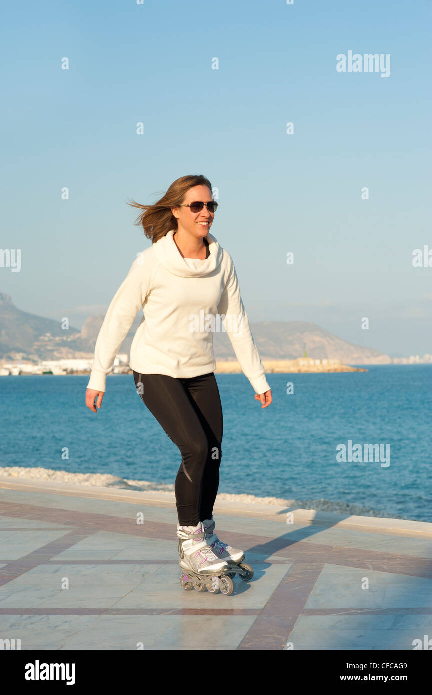 Woman skating along a sunny beach promenade Stock Photo - Alamy