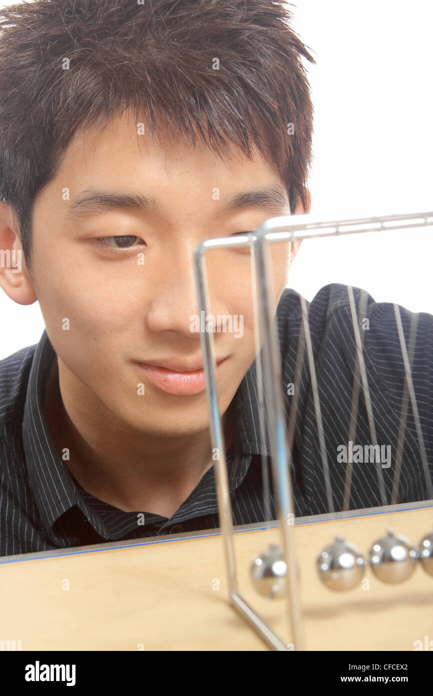 man moving Newton balls in office Stock Photo - Alamy