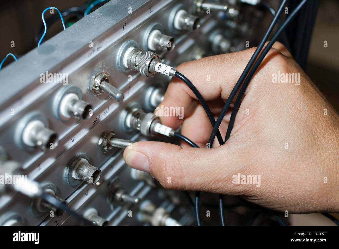 Hand switching plug on panel with different cables Stock Photo - Alamy