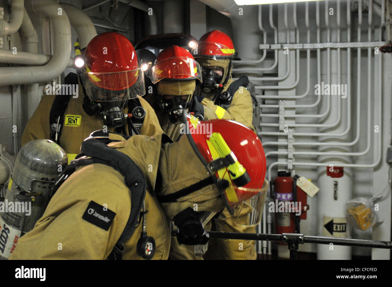 Sailors in a damage control repair party make their way into a space ...