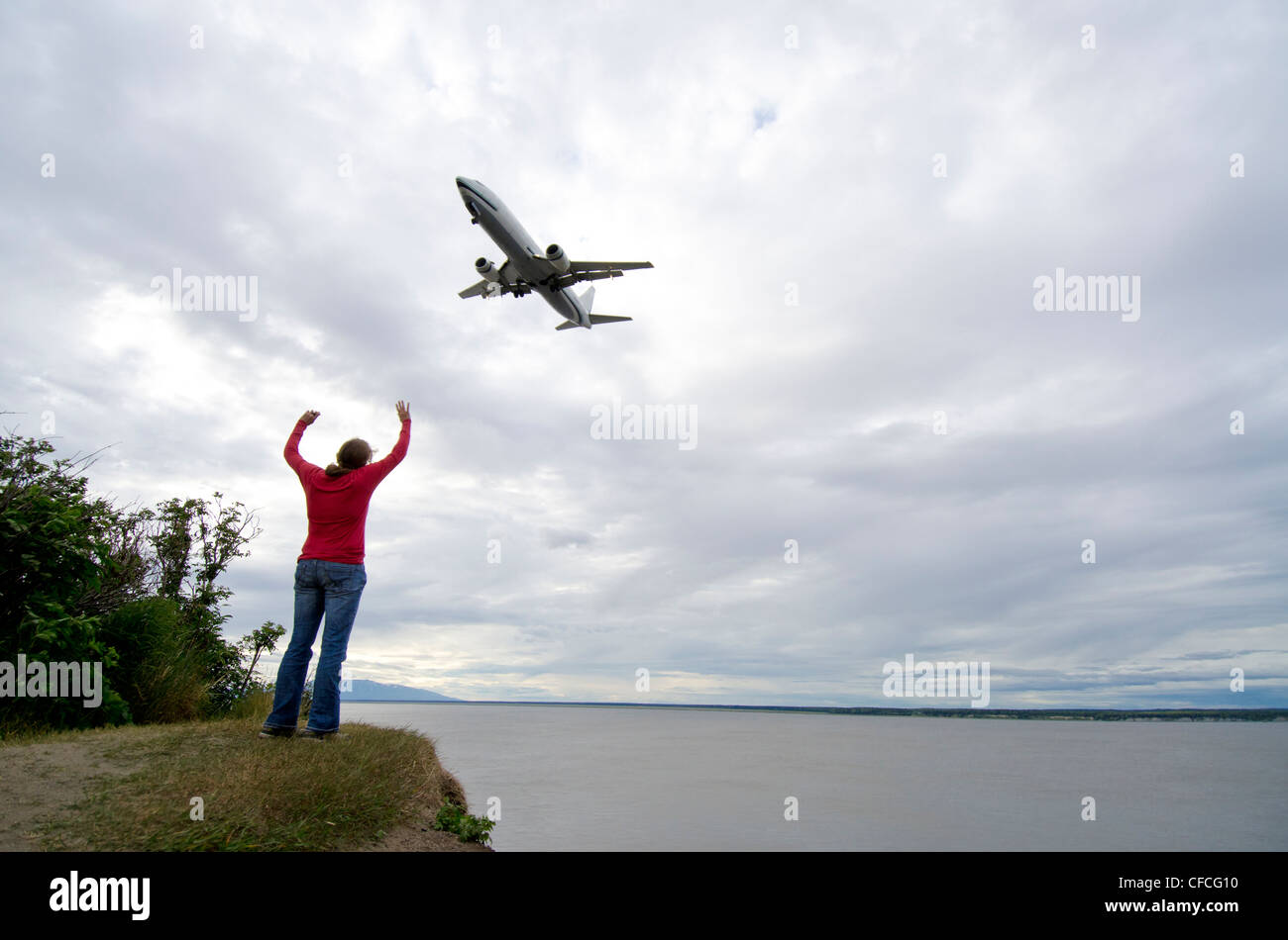 A young woman waves hello to a plane passing overhead in Anchorage ...