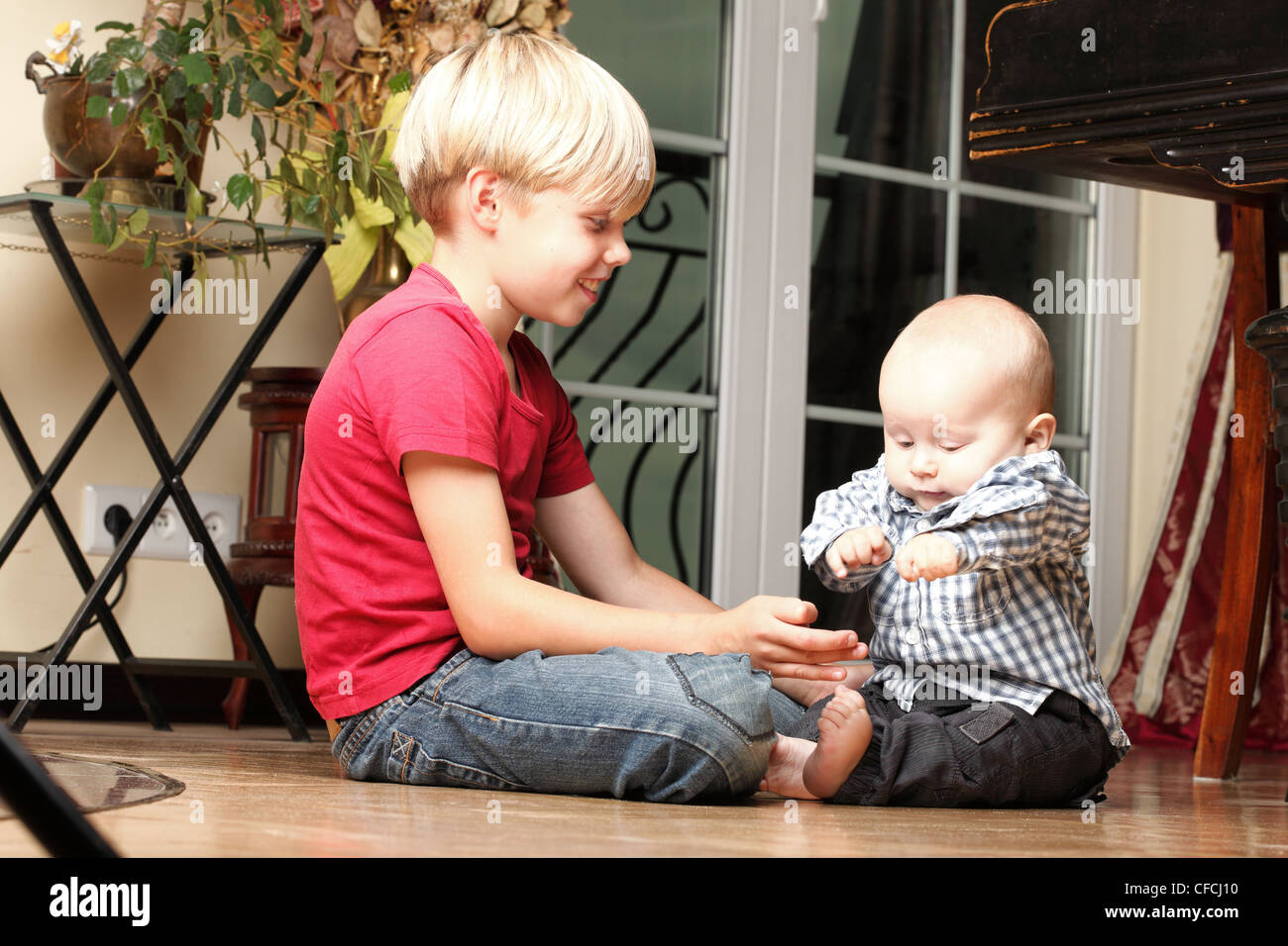 Blond boy with his newborn baby brother indoor, children playing Stock ...