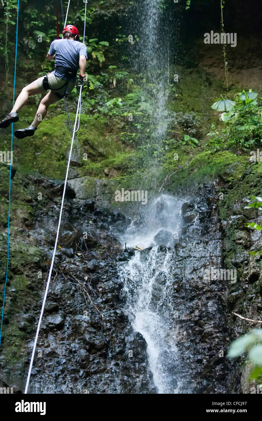 A man is canyoneering and rappelling around the waterfalls of Volcano ...