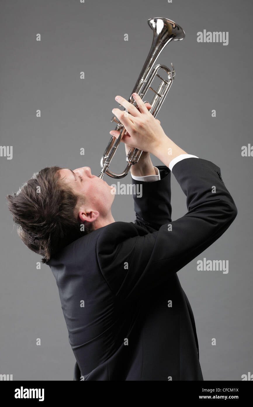Portrait of a young jazz man playing his Trumpet grey background Stock ...