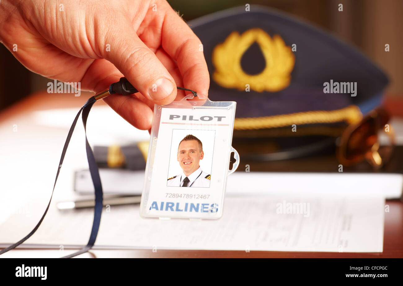Hand with professional airline pilot id holder, hat sun glasses laying ...
