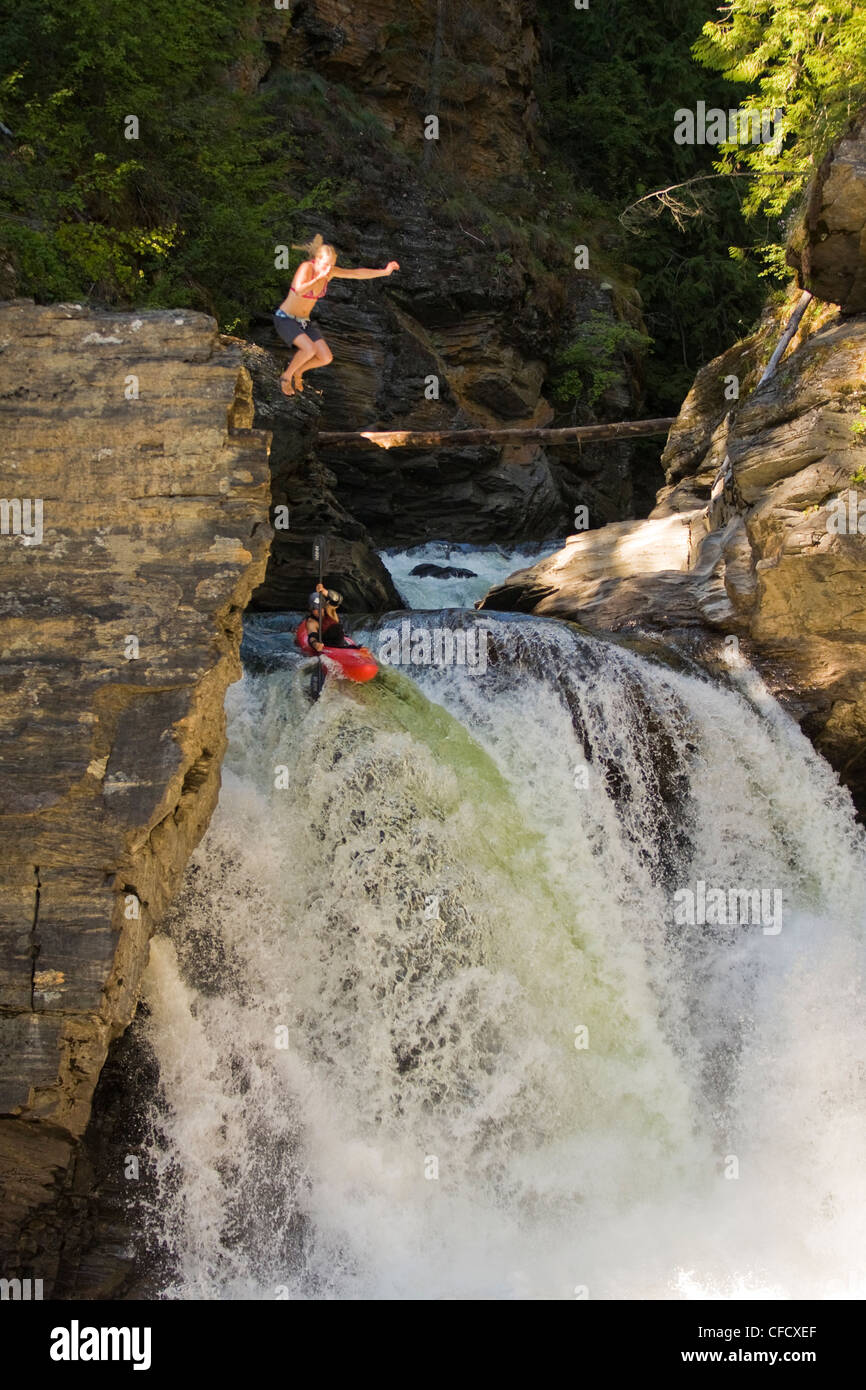 A woman cliff jumps as a man kayaks Raft Falls, Clearwater, British ...