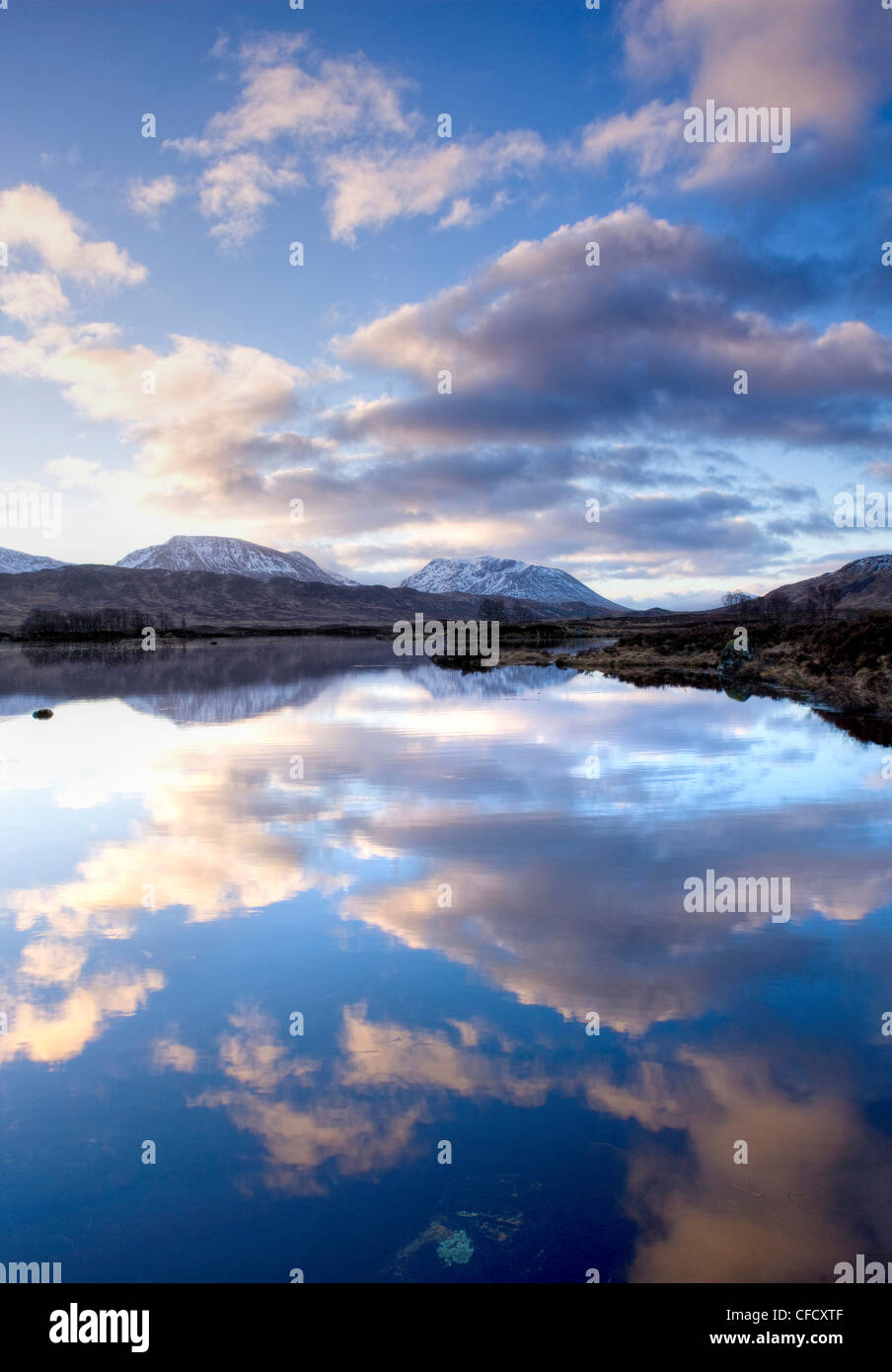 Dawn view of Loch Ba reflecting the sky and distant snow-capped ...