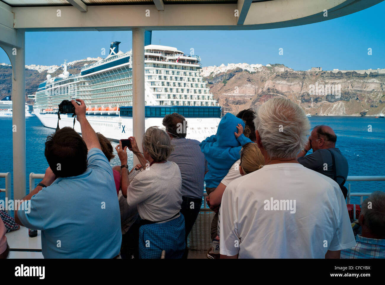 Tourists on board a ferry take photographs of a cruise ship in ...