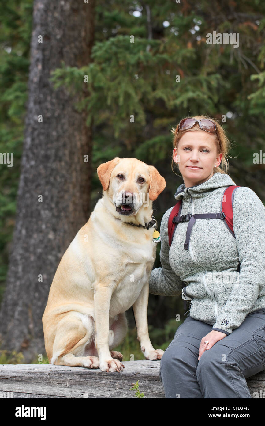 Portrait of woman hiker and her Yellow Labrador Retriever dog, sitting ...