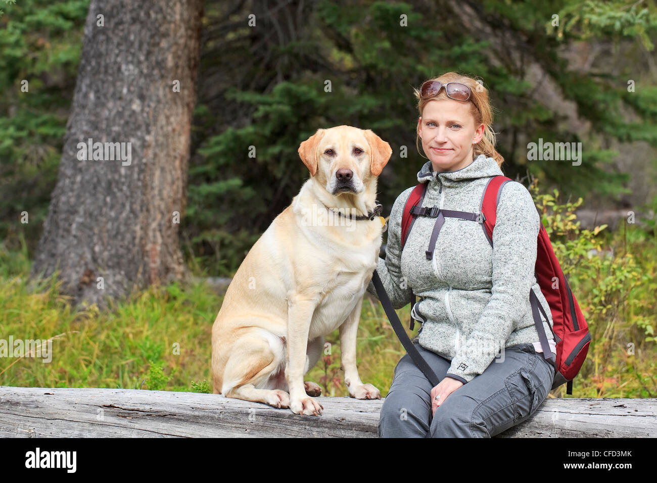Portrait of woman hiker and her Yellow Labrador Retriever dog, sitting ...