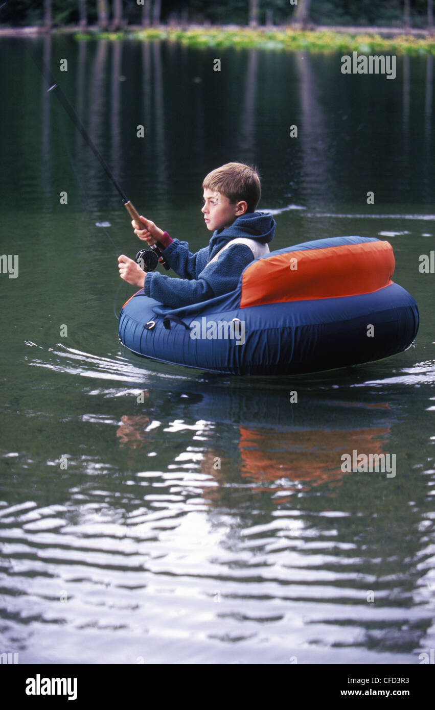 boy fly fishing from float tube in small lake, British Columbia, Canada ...