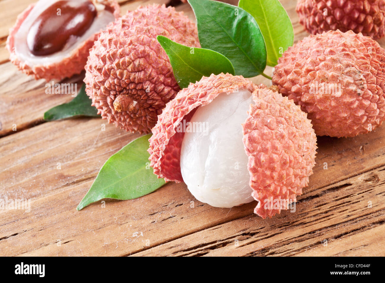 Lychee with leaves on a wooden table Stock Photo - Alamy