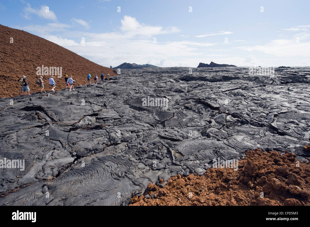 Tourists walking on lava flow on Isla Santiago, Sullivan Bay, Galapagos ...
