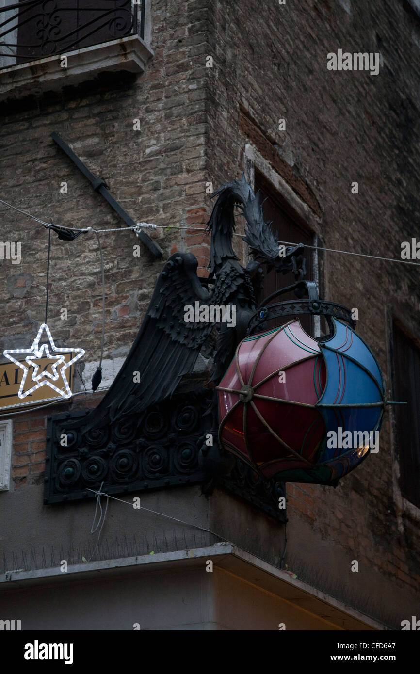 Statue on a wall of a dragon with umbrellas, shop sign in Venice Italy ...