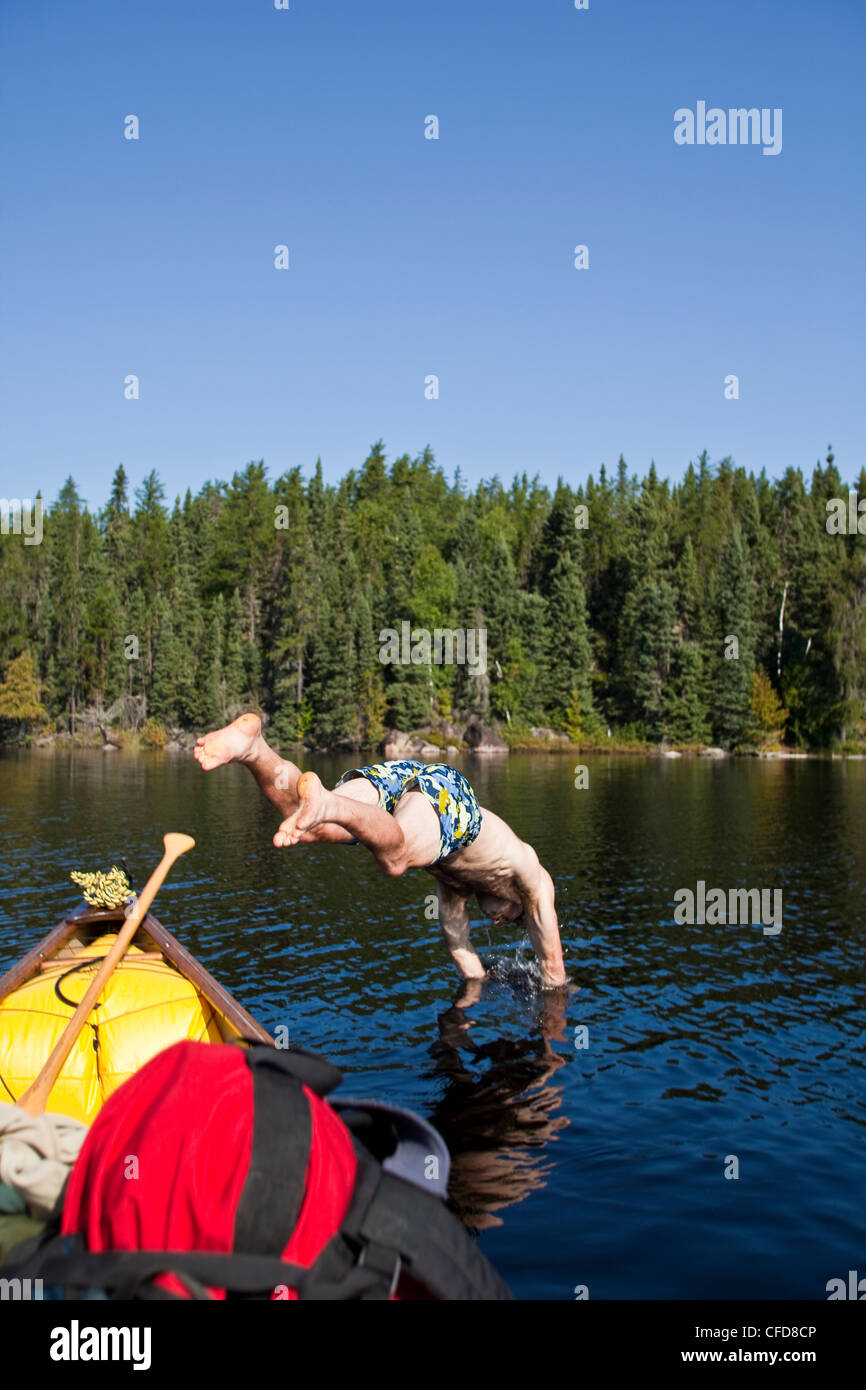 A man cooling off and diving into a lake on a hot day while canoeing ...