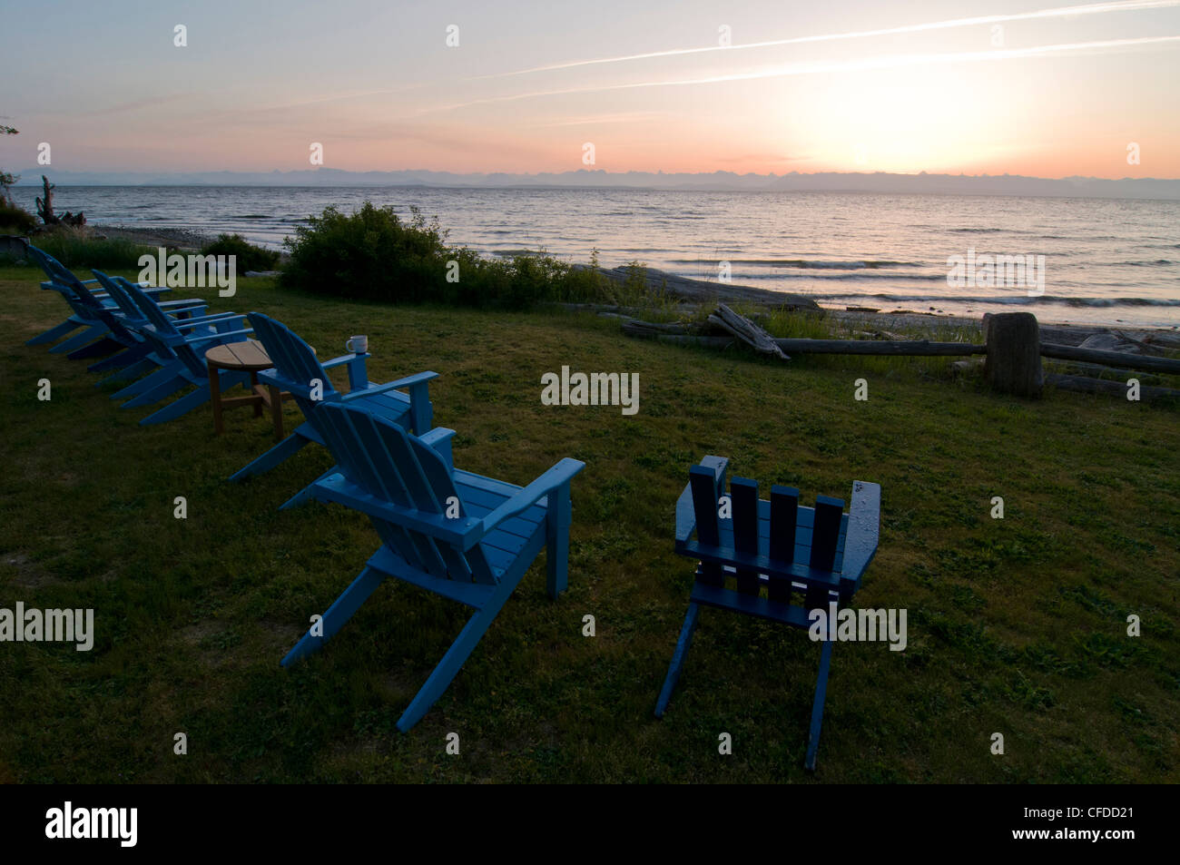 Adirondack chairs lined up on the beach at sunrise. Merville, British ...