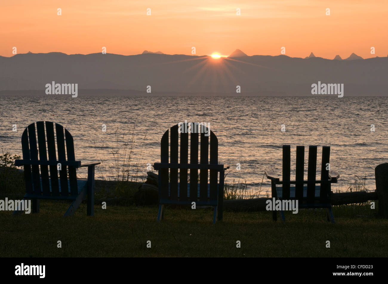 Adirondack chairs lined up on the beach at sunrise. Merville, British ...