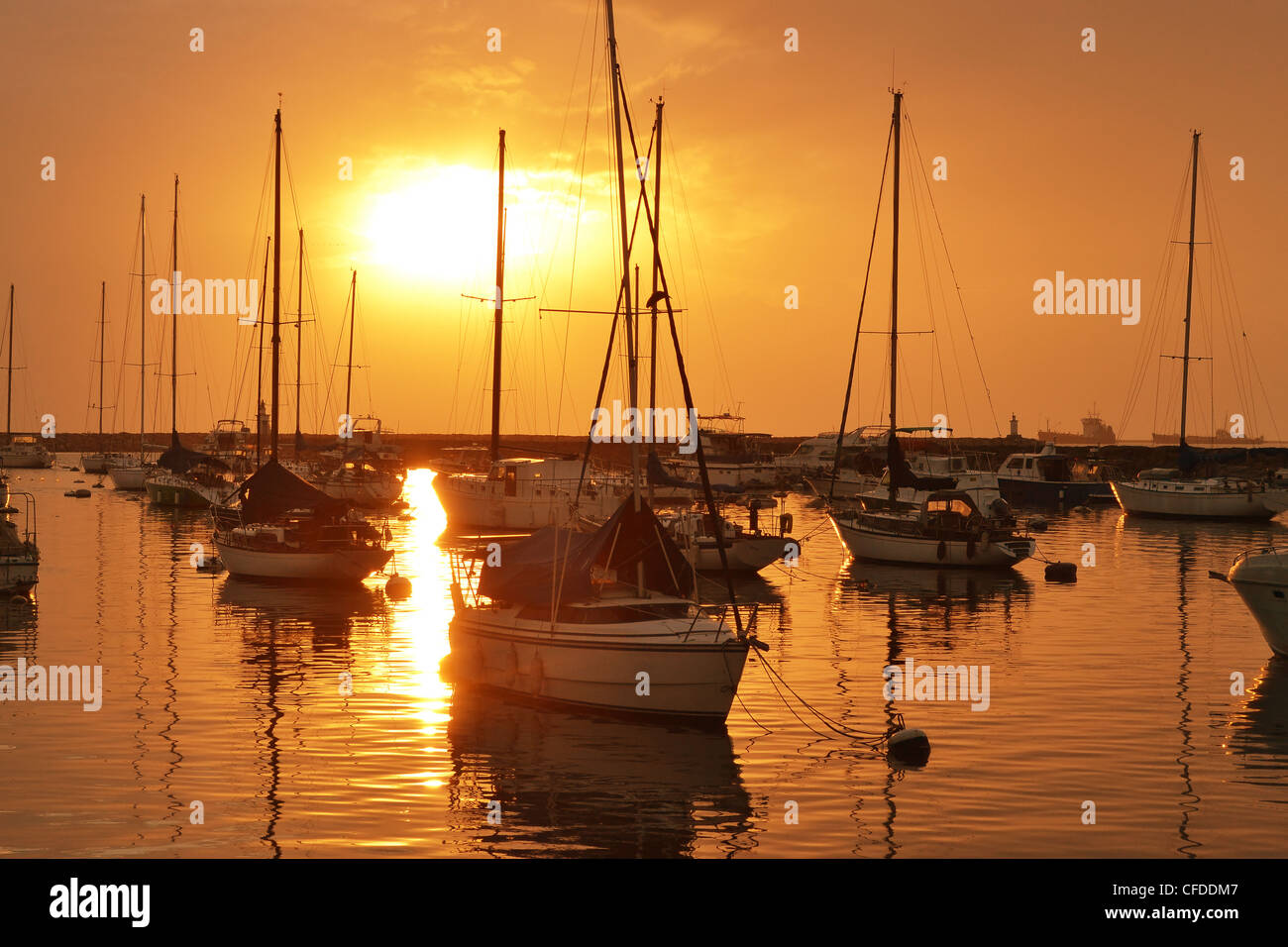 dramatic sun and sailboat reflection over calm water during sunset ...