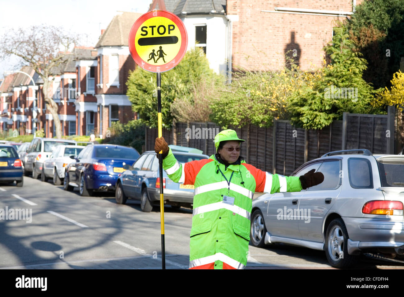 Lollipop lady helping school children cross road Stock Photo - Alamy
