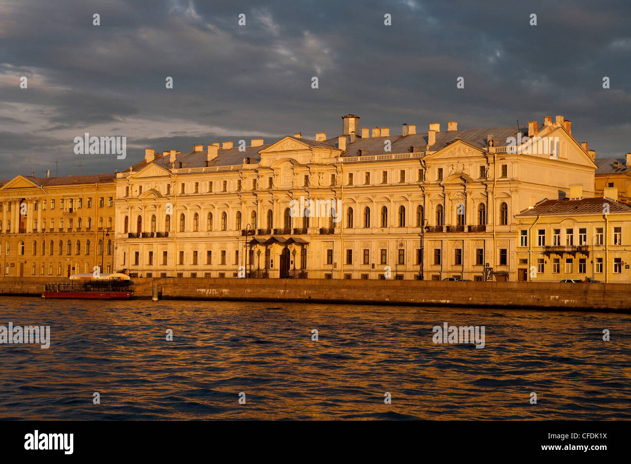 Golden-lit house facades along banks of Neva river, St. Petersburg ...