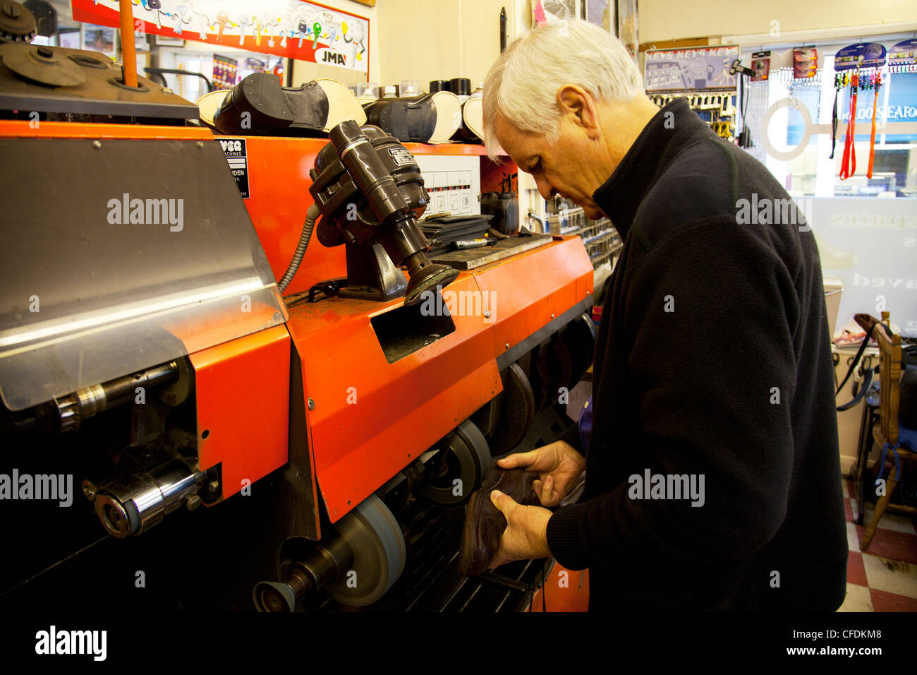 Shoe repairer mending shoes in cobblers shop working on machine to ...